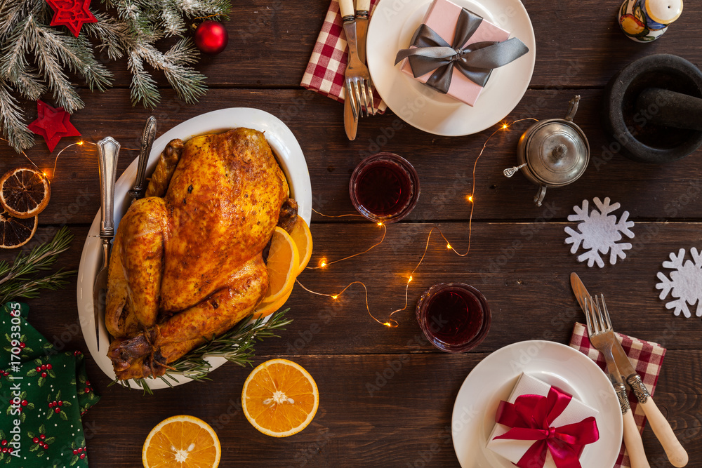 Christmas festive table is decorated with a garland. Baked chicken as a ...