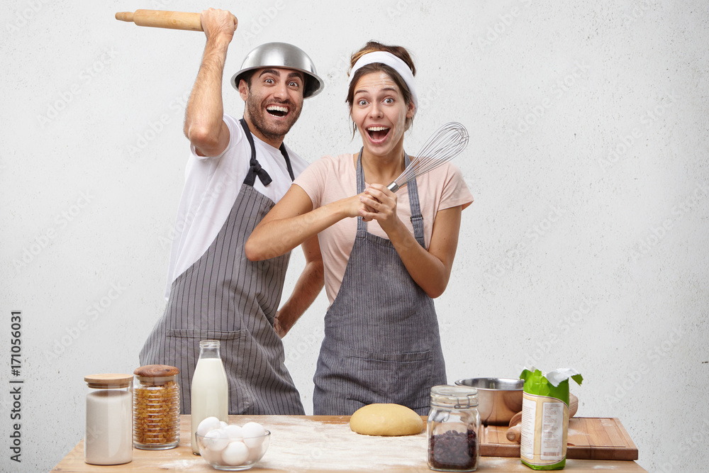 Funny excited couple have joy together at kitchen, fight with rolling ...