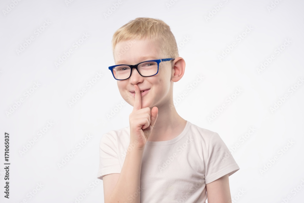 young boy kid shows sign hand gesture holding finger on lips. Stock ...
