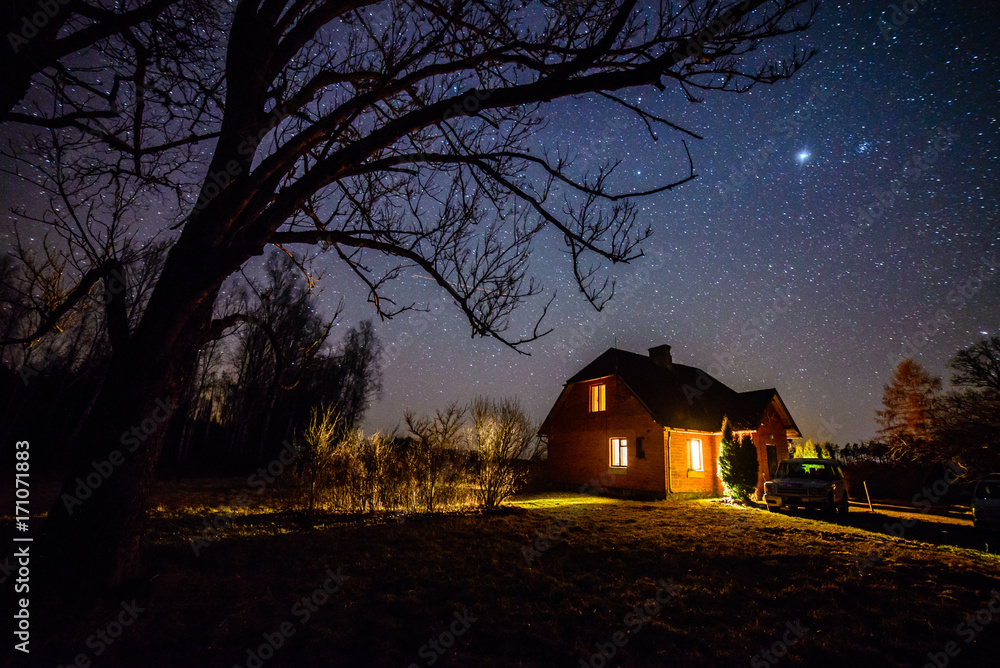 The Milky Way in night sky with stars over wooden country house at ...