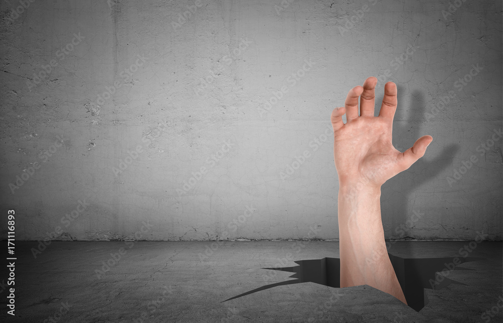A large male hand forcing its way through a hole in a concrete surface ...