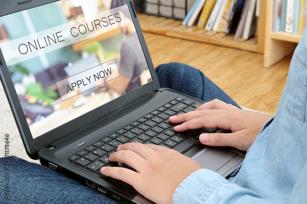 Hand typing labtop computer with online courses on screen background ...
