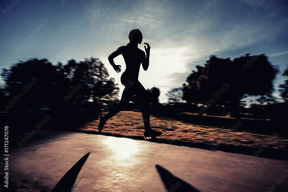 A silhouette of an athlete running on a track behind the sunset. Stock ...