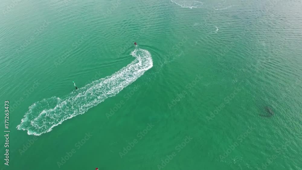 Forward flight over ocean water passing fast sailing jet ski vídeo de ...