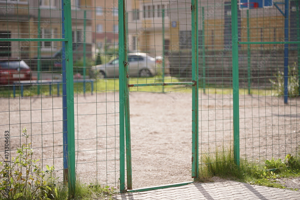 Broken steel mesh of metal fence of a basketball court in residential ...