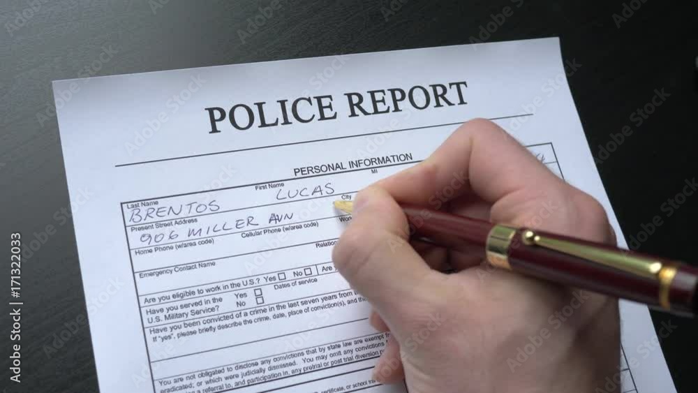 Filing a police report by hand at a desk. This form is randomly filled ...