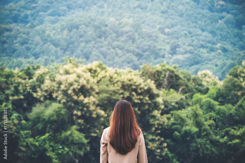 A woman turn back and standing alone with green nature and mountain ...