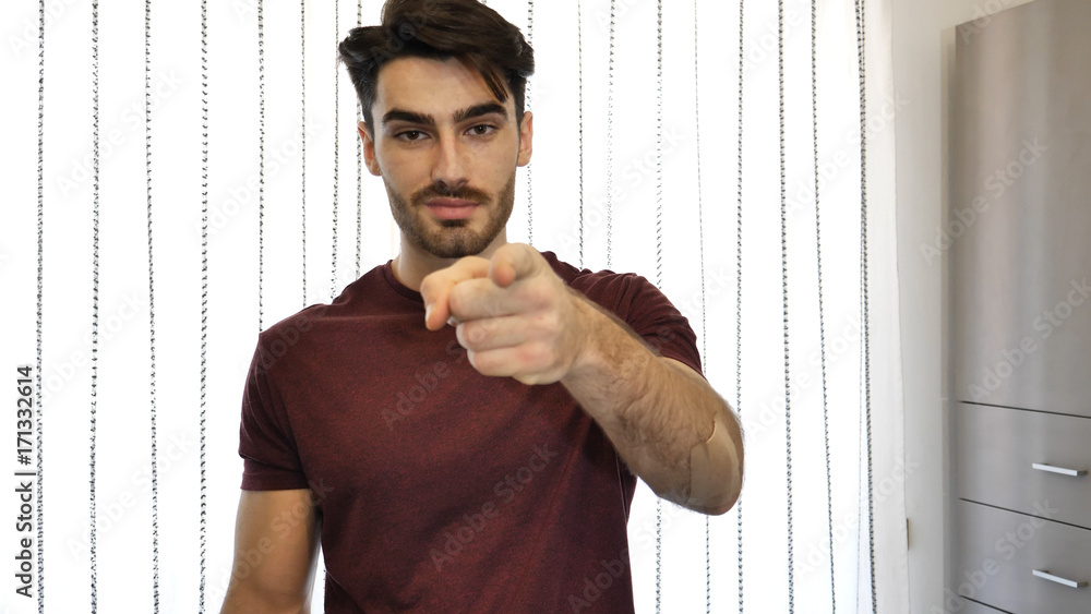 Handsome young man gesturing with his hand, pointing finger at you ...