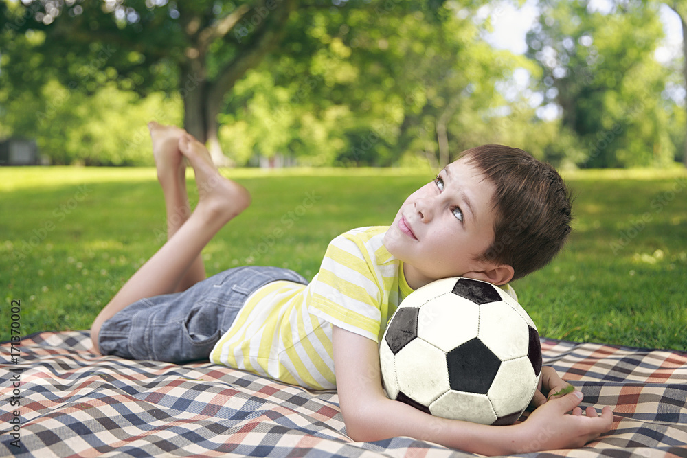 Boy resting with a soccer ball. cute kid lying in the park relaxing ...