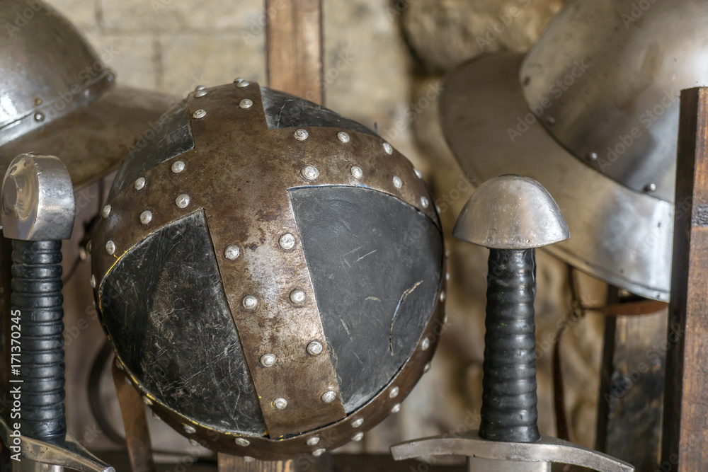 Detail of several medieval helmets helms and sword ready for battle ...