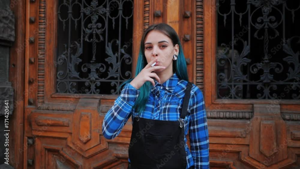 Stockvideon Young Punk Girl Smoking Cigarette By The Wooden Door