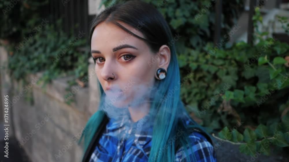 Young attractive punk girl smoking cigarette. Hipster with blue unusial ...