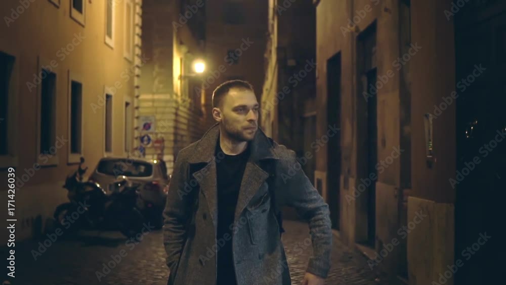 Slow motion. Young handsome man walking through the deserted street ...