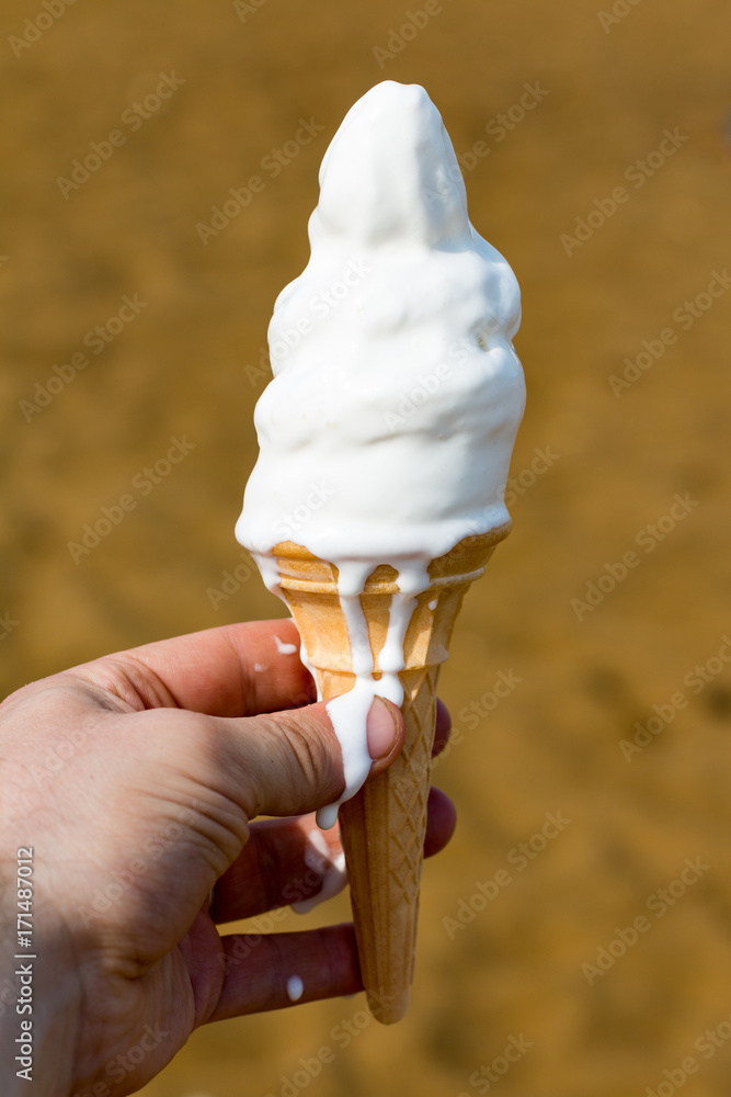 A vanilla whippy ice cream cone melts in the hot summer weather ...