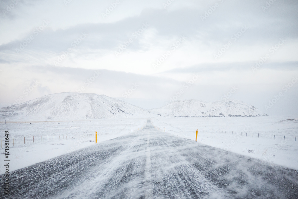 Straight road in snow covered landscape and stormy weather, Route 1 ...