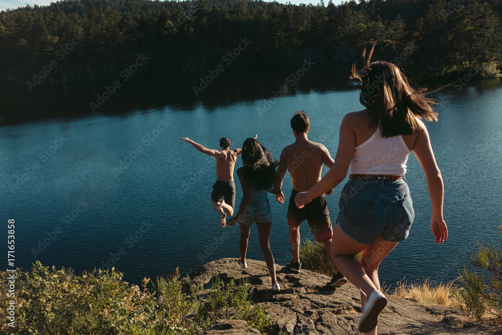 Young, brave friends running to jump off cliff into lake Stock Photo ...