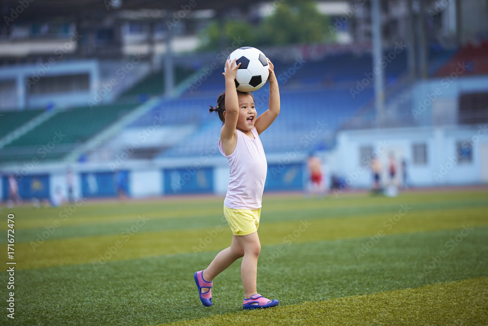Little girl playing football outdoor in the football field Stock Photo ...