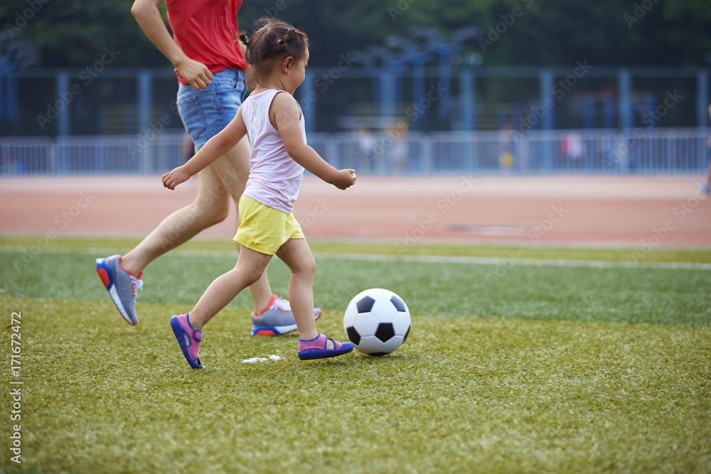 Little girl playing football outdoor in the football field Stock Photo ...