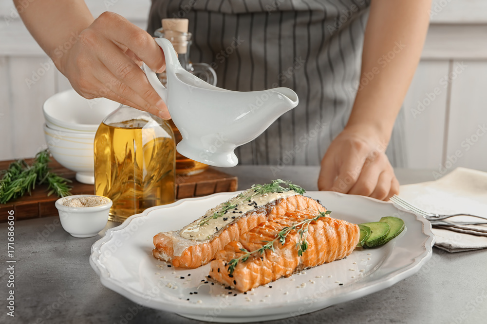Woman pouring fish sauce onto plate with delicious salmon Stock Photo ...
