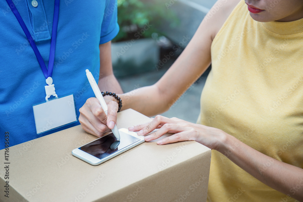 Woman appending signature after accepting a delivery of boxes from ...