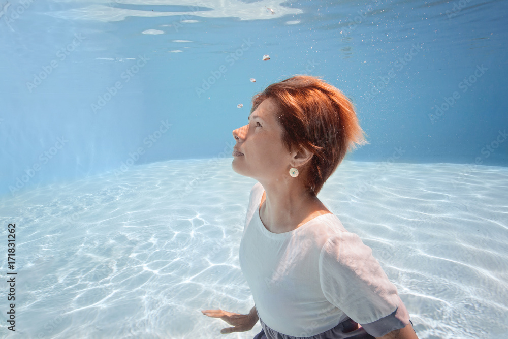 young woman in blue and white dress swim and dive underwater floating ...