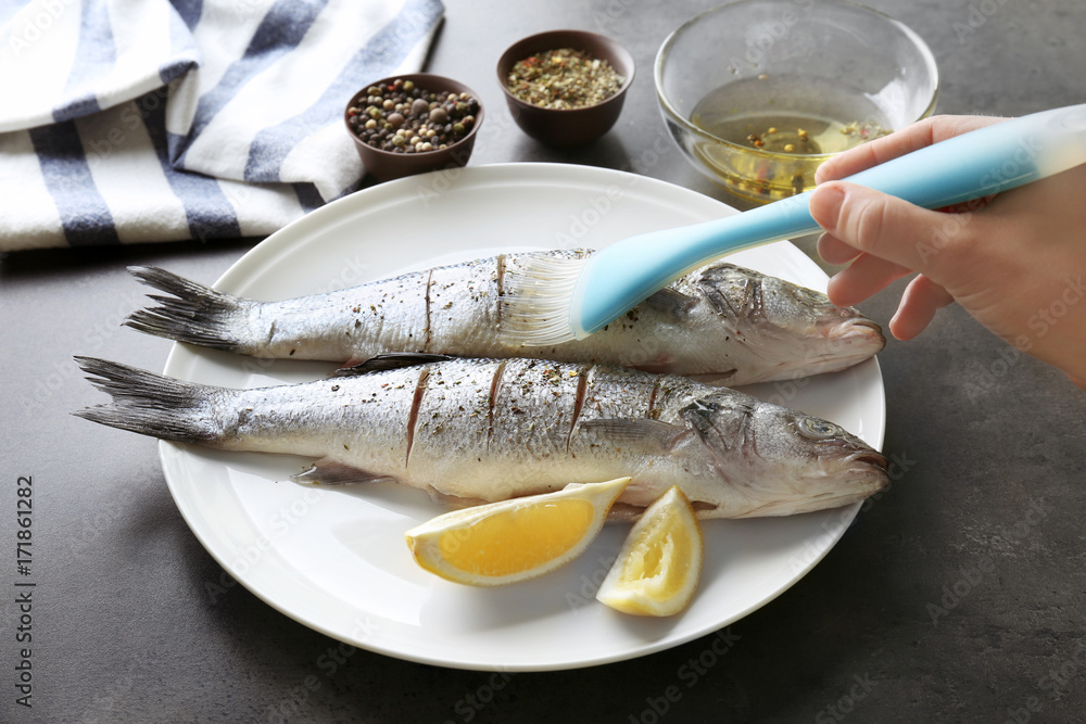 Woman preparing fresh fish with slices of lemon on plate Stock Photo ...