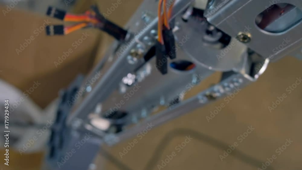 A close-up view of a robotic humanoid arm with wires, cables and screws ...