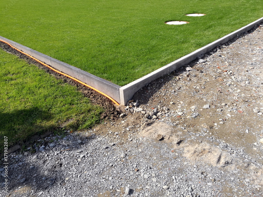 Grüner englischer Rasen mit Gullydeckel und rechtem Winkel in einem ...