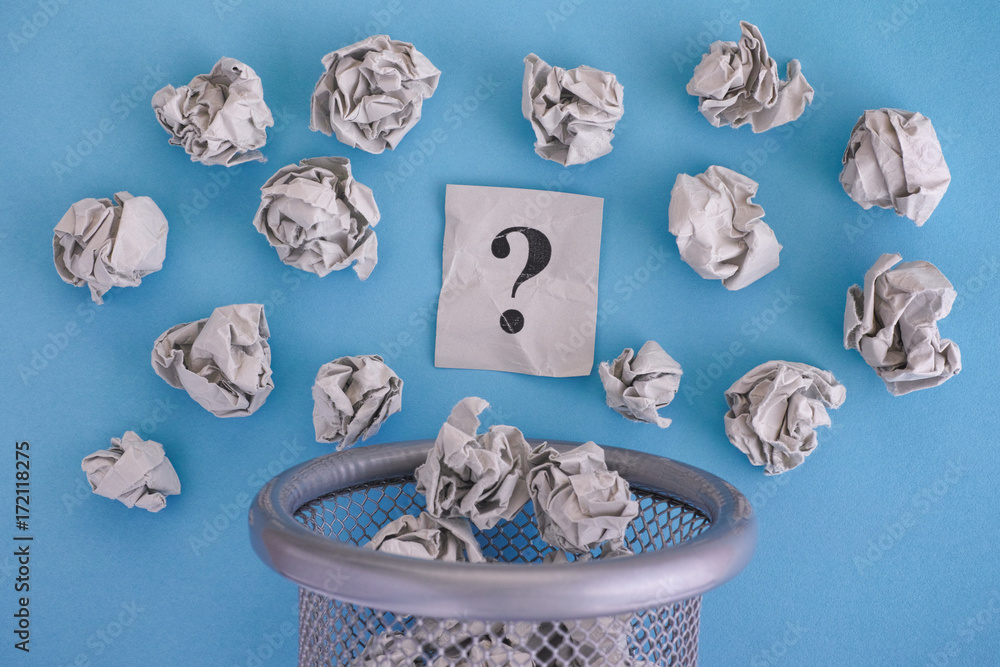 Gray crumpled paper balls and question mark rolling out of a trash can ...