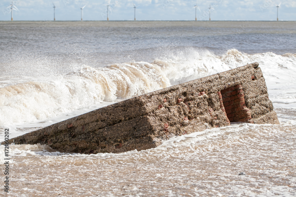 Rising sea level. Wave flooding beach and engulfing historical WW2 ...