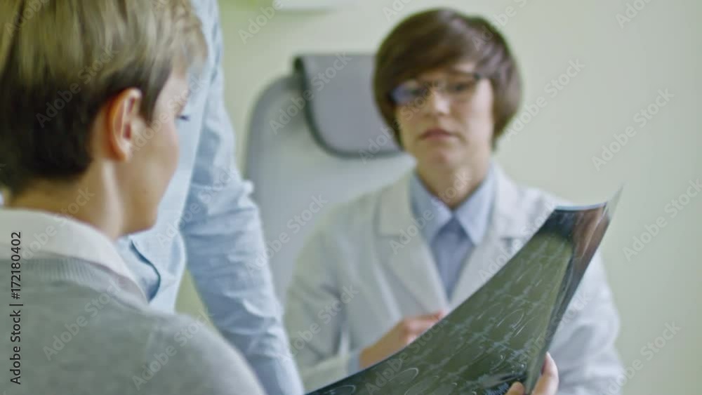 PAN with rack focus of young woman taking MRI scan of brain from female ...