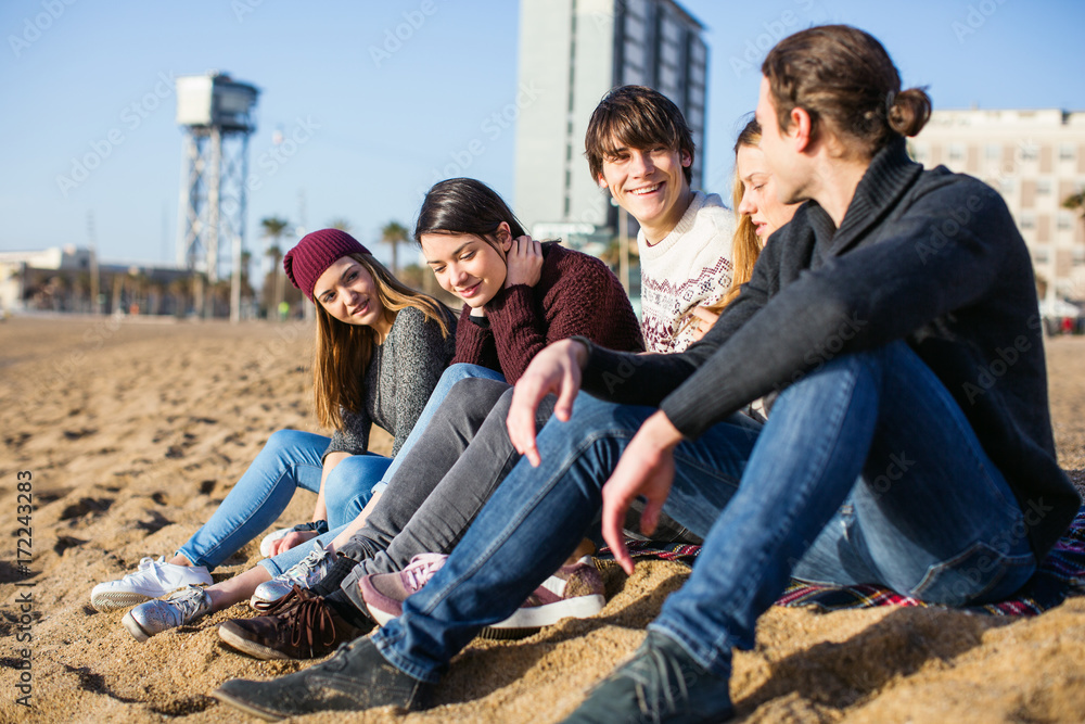 Foto de Teenage friends hanging out sitting on the beach. do Stock ...