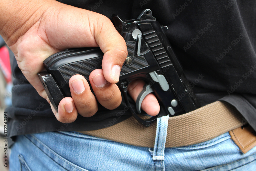 gangster concealing his gun behind his back Stock Photo | Adobe Stock
