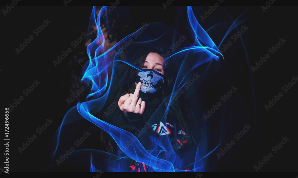 Rebellious youth: Girl wearing a skull mask showing the middle finger ...