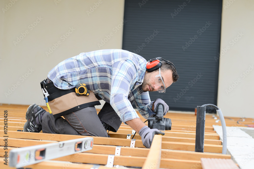 handsome young man carpenter installing a wood floor outdoor terrace in ...