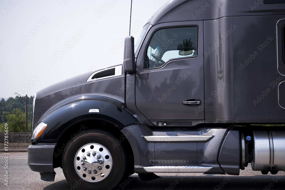 Dark grey powerful modern big rig semi truck tractor profile runing on ...