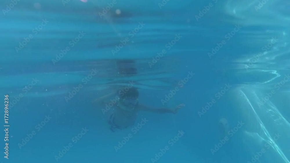 Boy dive in swimming pool and looking at the camera, underwater shoot ...