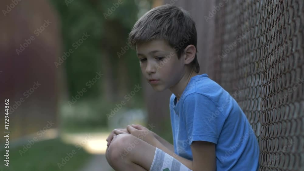 Sad upset abused teenager boy sitting alone, lonely serious offended ...