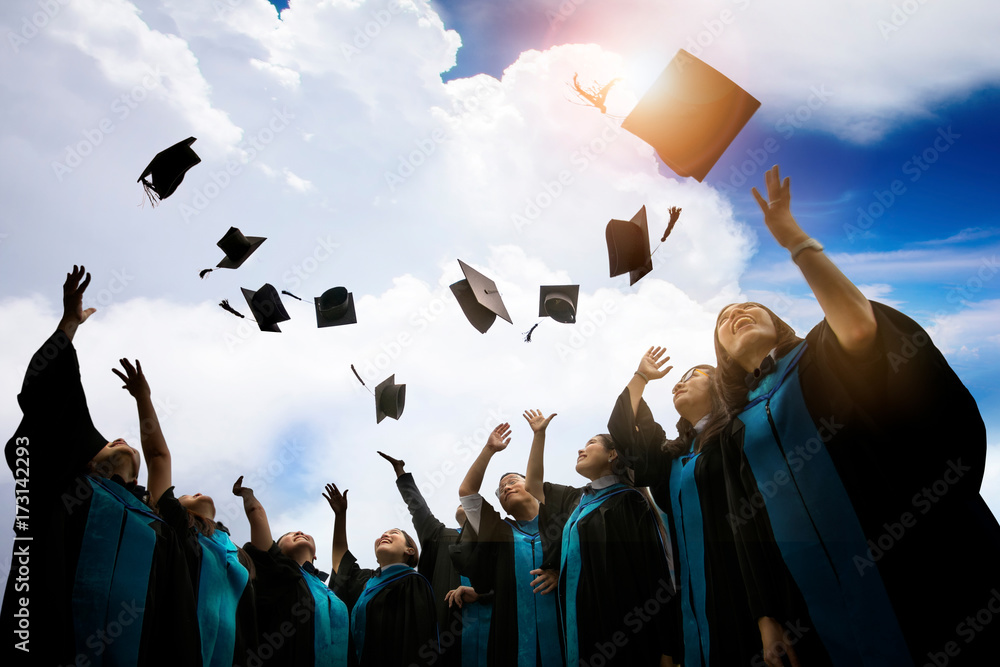 Group of graduates with congratulations throwing graduation hats in the ...