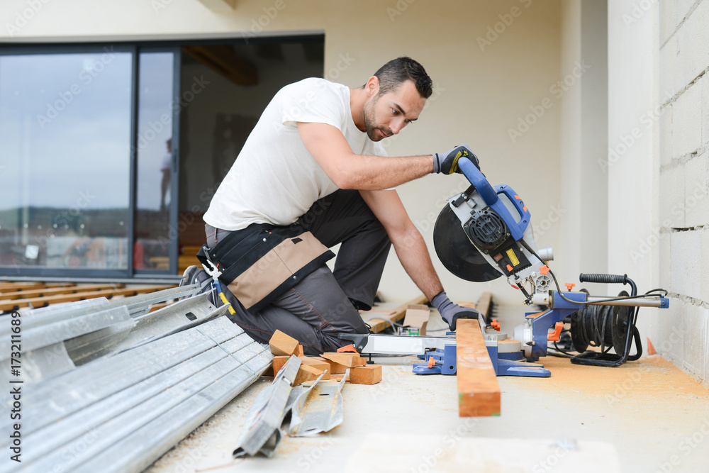 handsome young man carpenter using a circular saw while installing wood ...