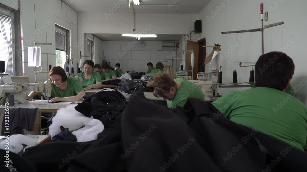 Group of female dressmakers sitting and using sewing machines to ...