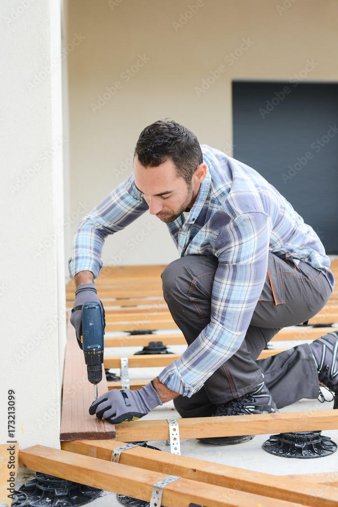 handsome young man carpenter installing a wood floor outdoor terrace in ...