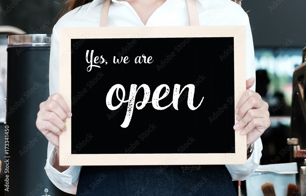 Hand holding open sign chalkboard in font of cafe counter background ...