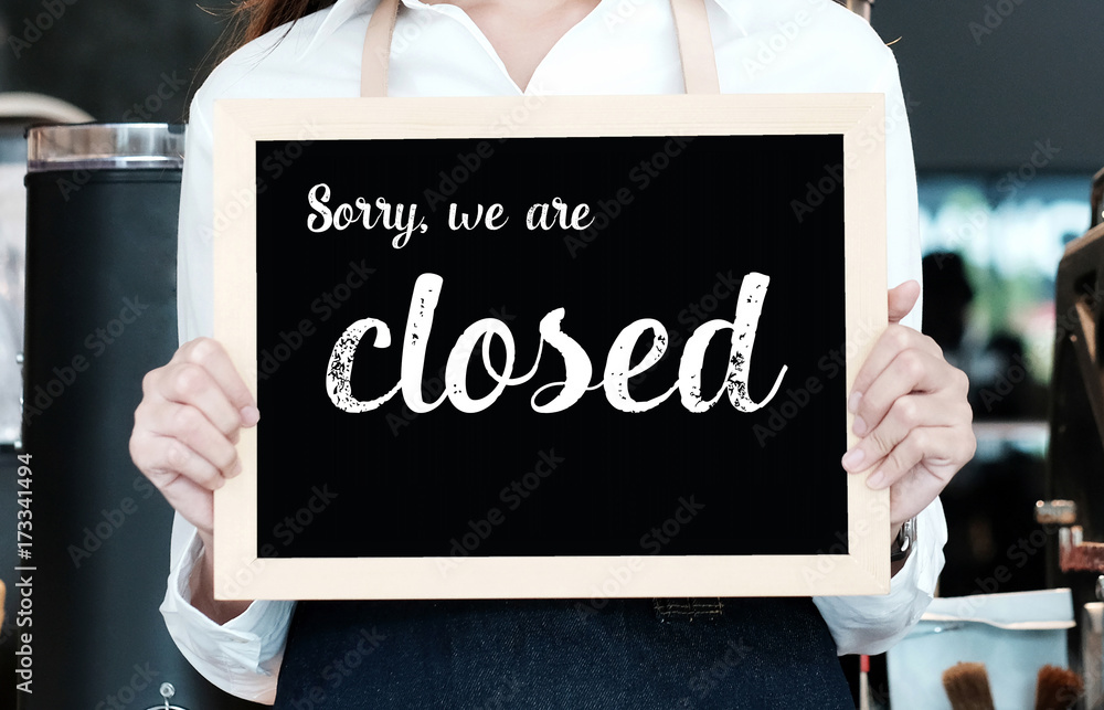 Hand holding closed sign chalkboard in font of cafe counter background ...