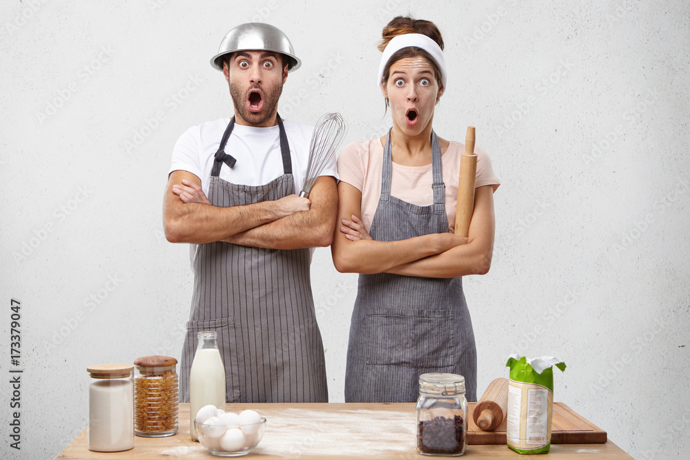 Portrait of male and female cookers prepare dinner for guests, look ...