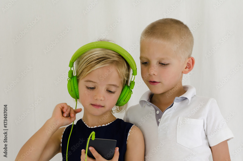 Cute little girl with headphones and cute little boy listening to music ...