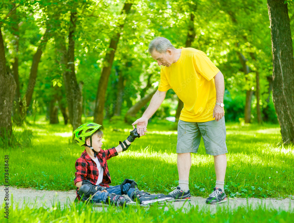 Father helps to rise to the son who has fallen down rolling on roller ...