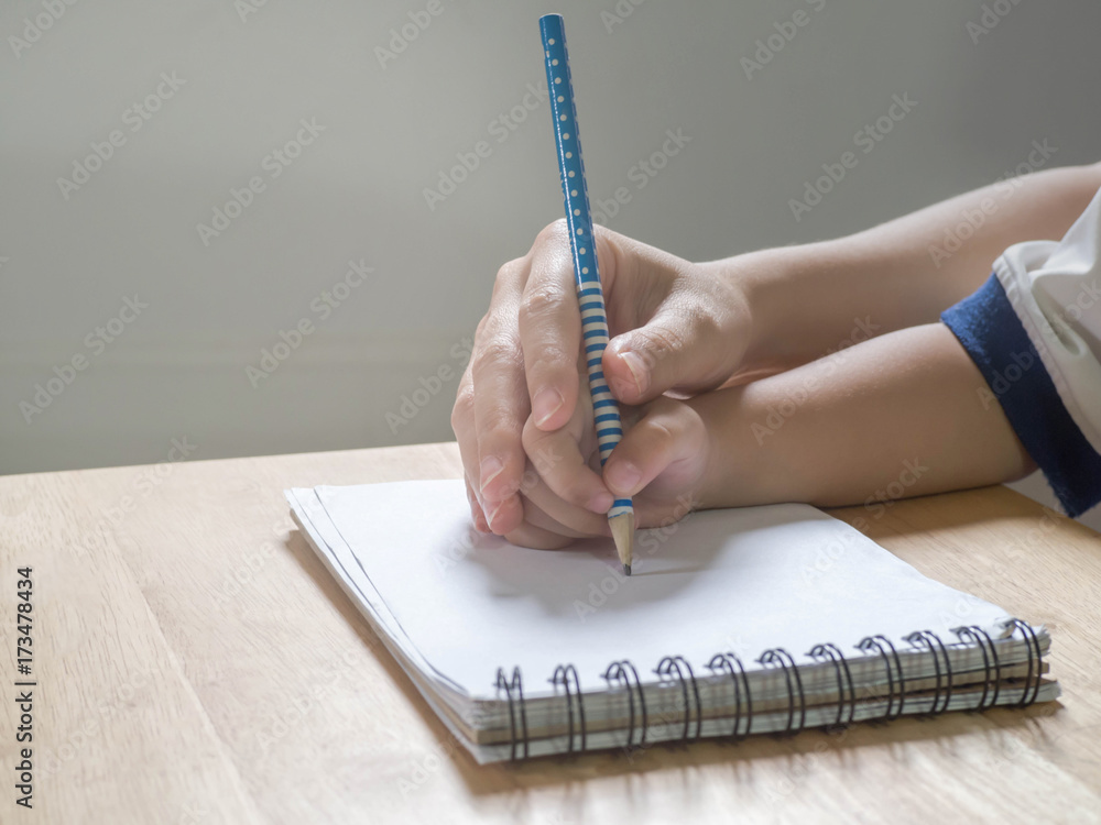 Adult hand holding child hand to write on notepad.Concept of learning ...