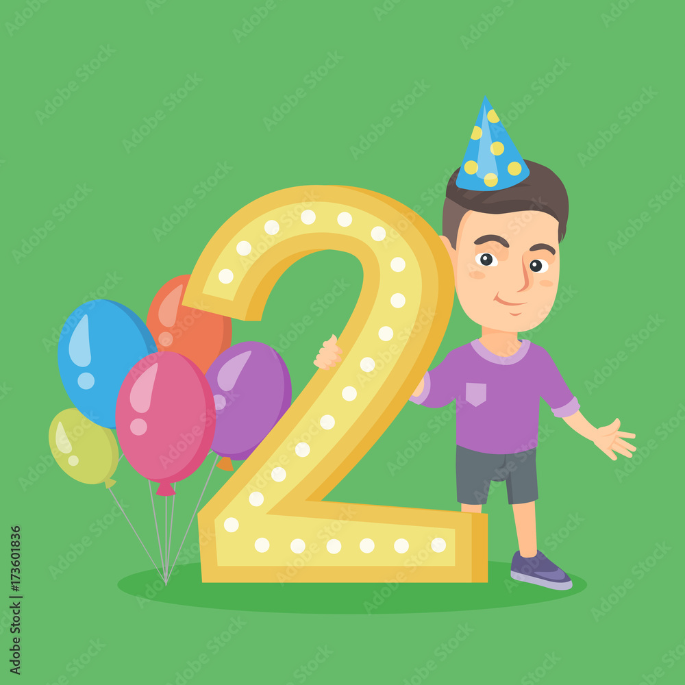 Little caucasian boy standing next to the number two and balloons at ...