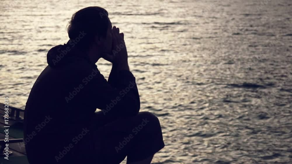 Silhouette of depressed sad man sitting by the lake in cold autumn ...